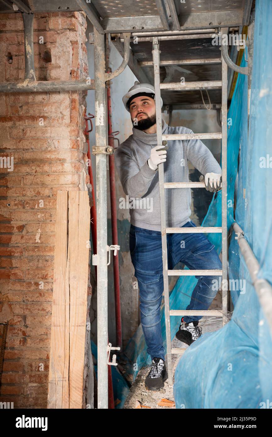 Man ascending up ladder during house reconstruction Stock Photo - Alamy