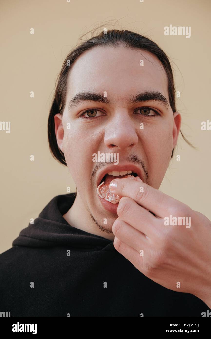 young Caucasian guy bites sour unripe citrus. A man makes a face ...