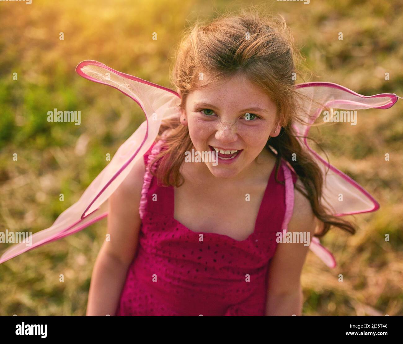 Pretty as a picture in pink. Portrait of a cute little girl looking up ...