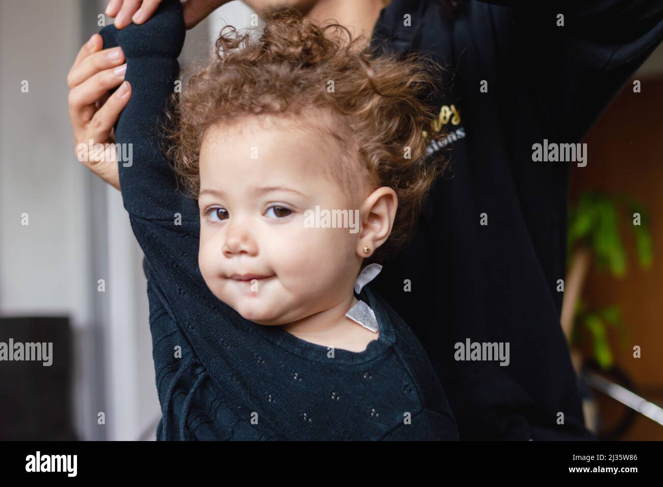 Caucasian baby standing in the living room looking at the camera in ...