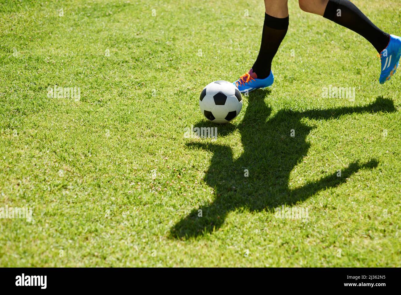 The art of dribbling. Shot of a young footballer dribbling the ball on ...