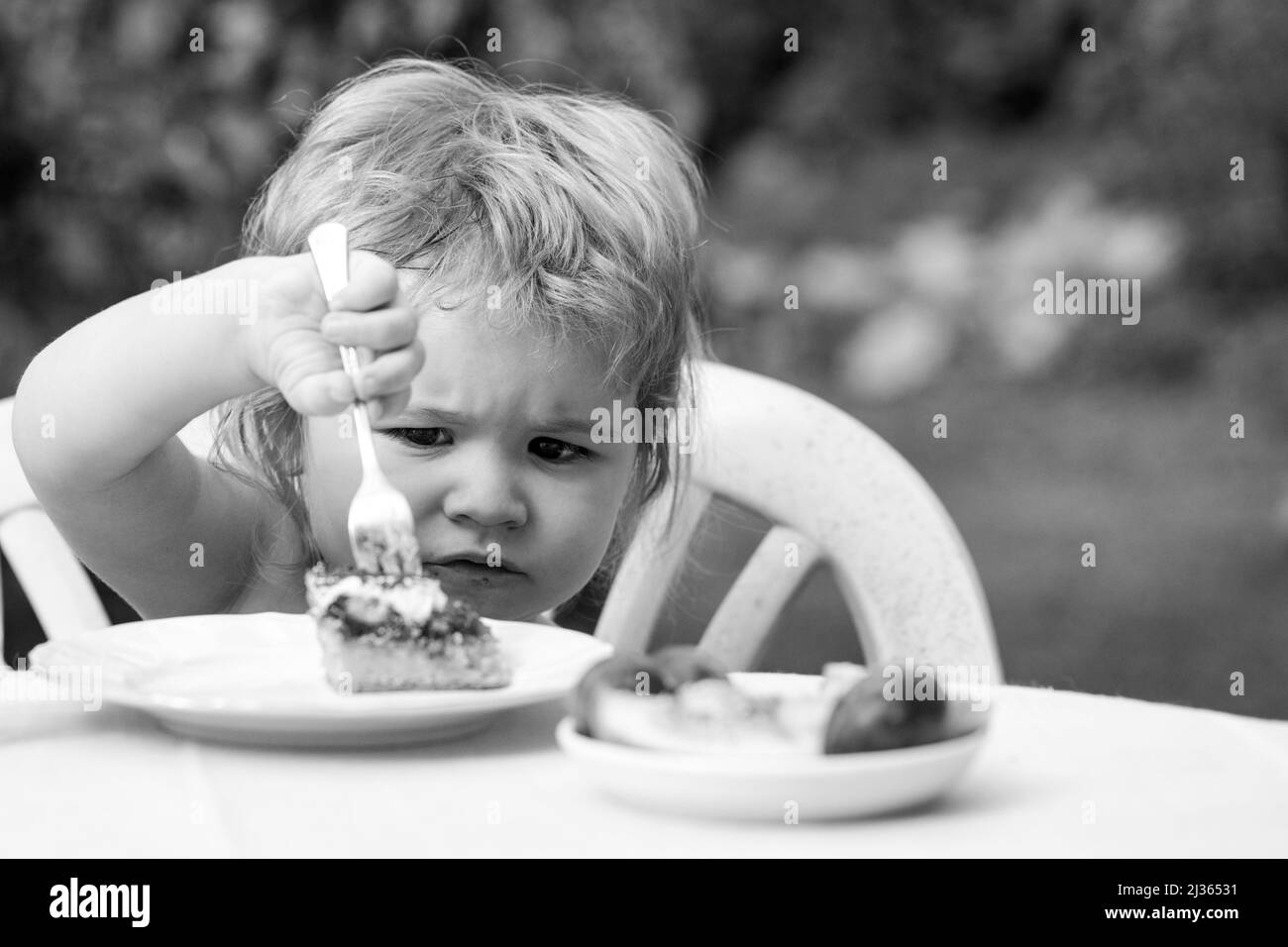 Baby eating cake. Little child eats cake in nature at a picnic. The ...