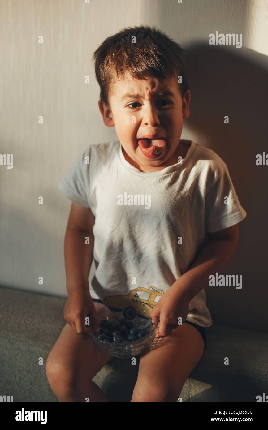 Boy disgusted by a disgusting blueberry that he eat. Facial expression ...