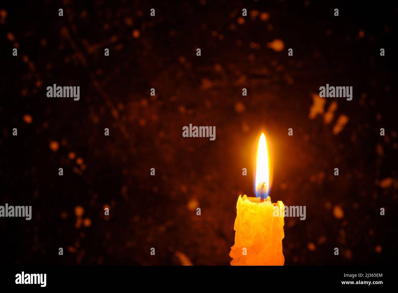 Candle burning brightly against dark wall Stock Photo - Alamy