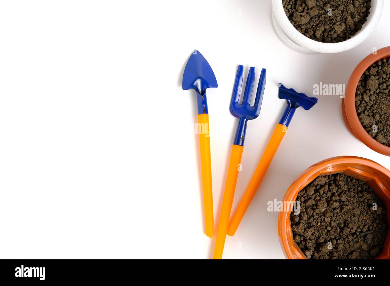 Flower pots with earth and set decorative garden tools on white ...