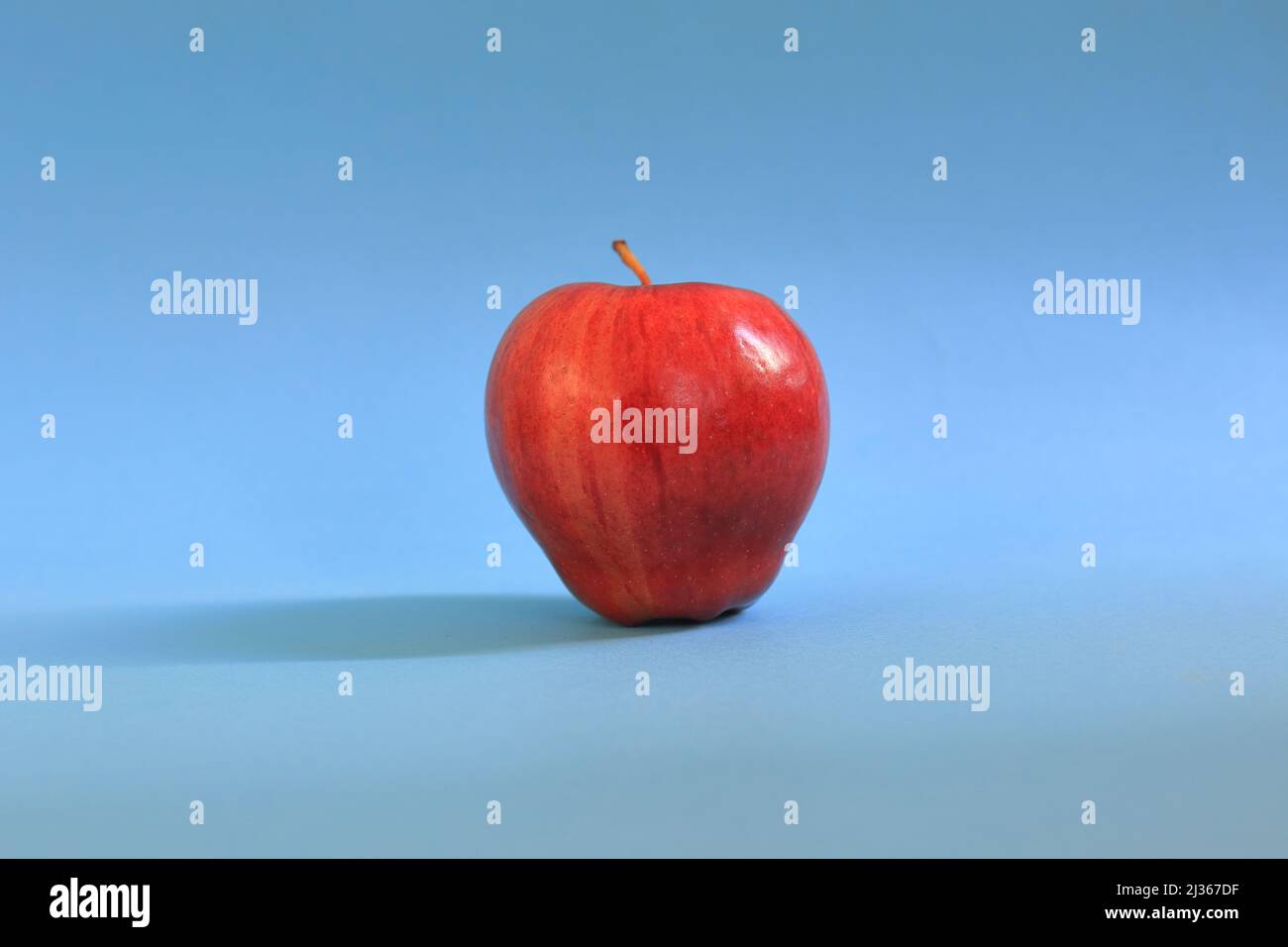 A red apple on a blue background Stock Photo - Alamy