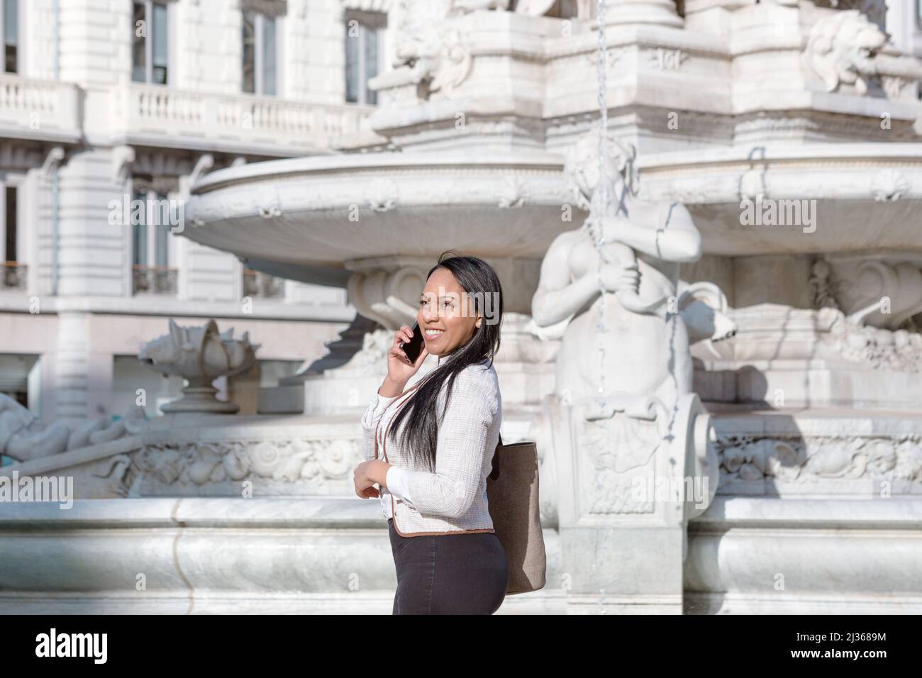 A young multiracial woman talking on her phone in the square of ...