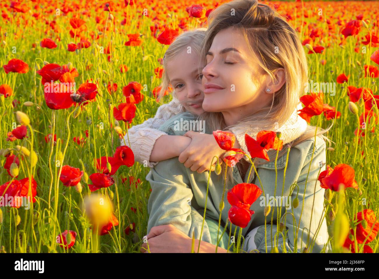 Mother and daughter hugging on spring blossom field. Mom with a child ...