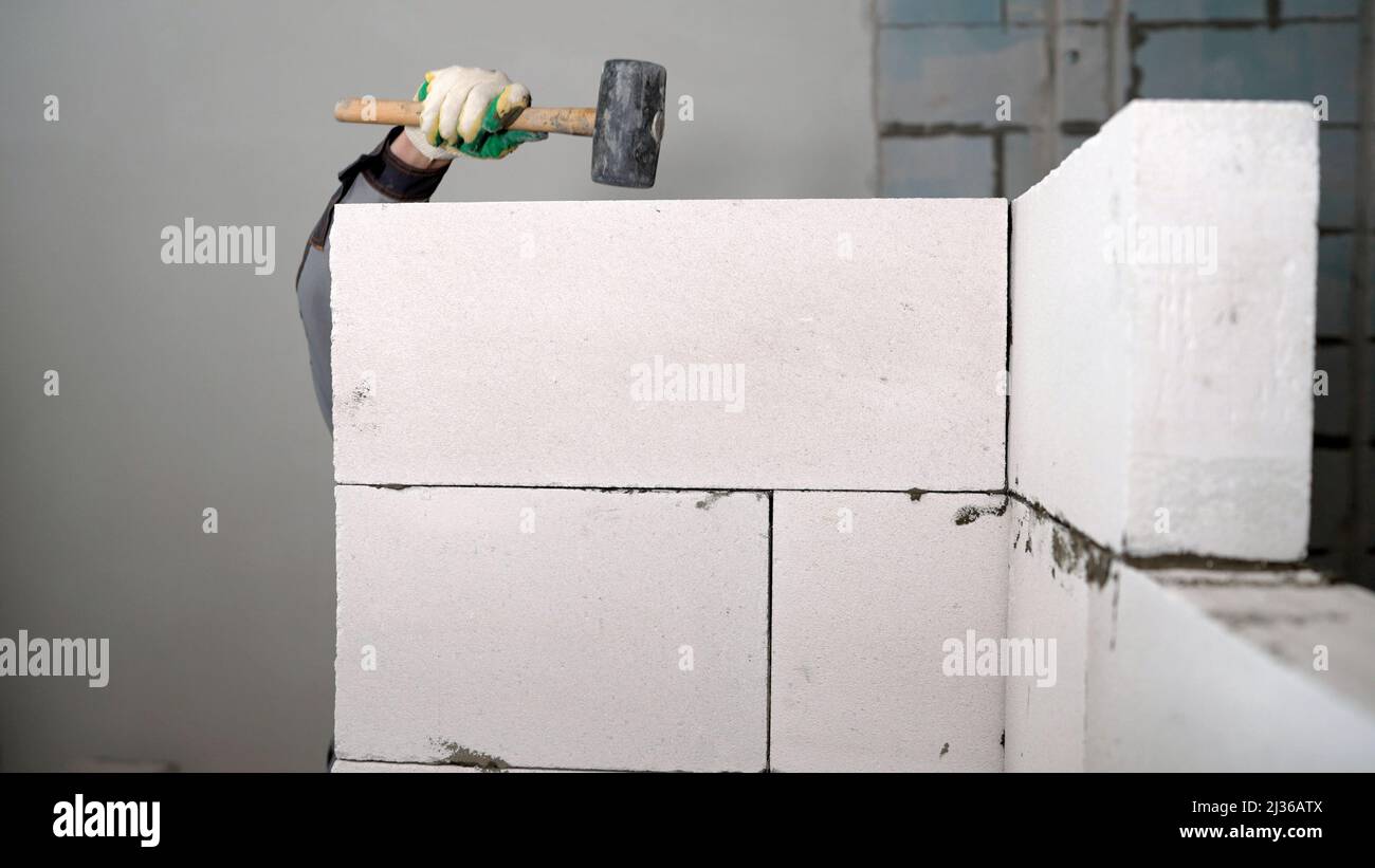 The process of building a wall of aerated concrete blocks. A worker ...