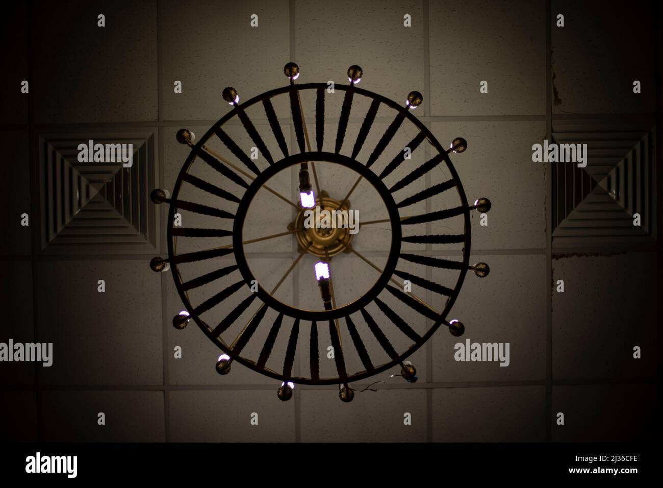 Round chandelier on ceiling. Lamps are shining. Old copper chandelier ...