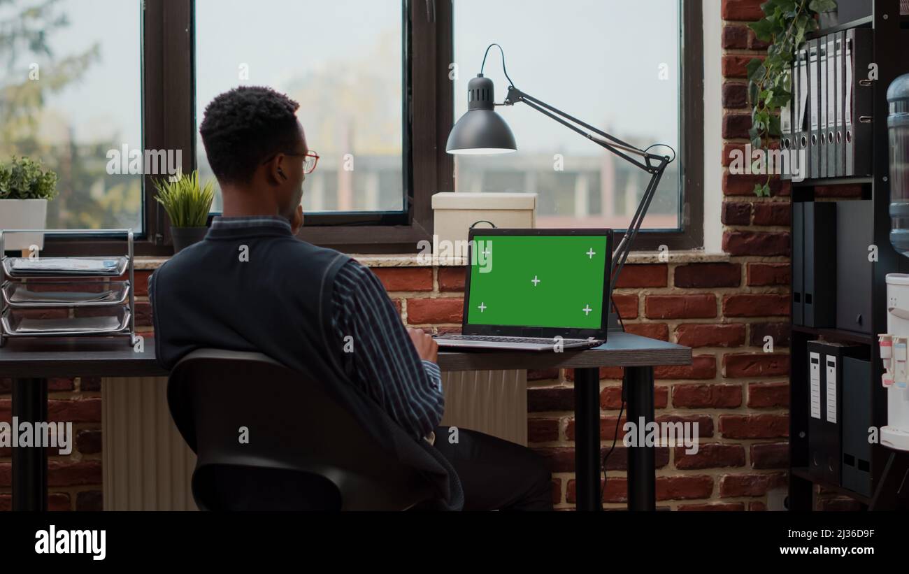 Male secretary analyzing green screen on laptop in startup office ...