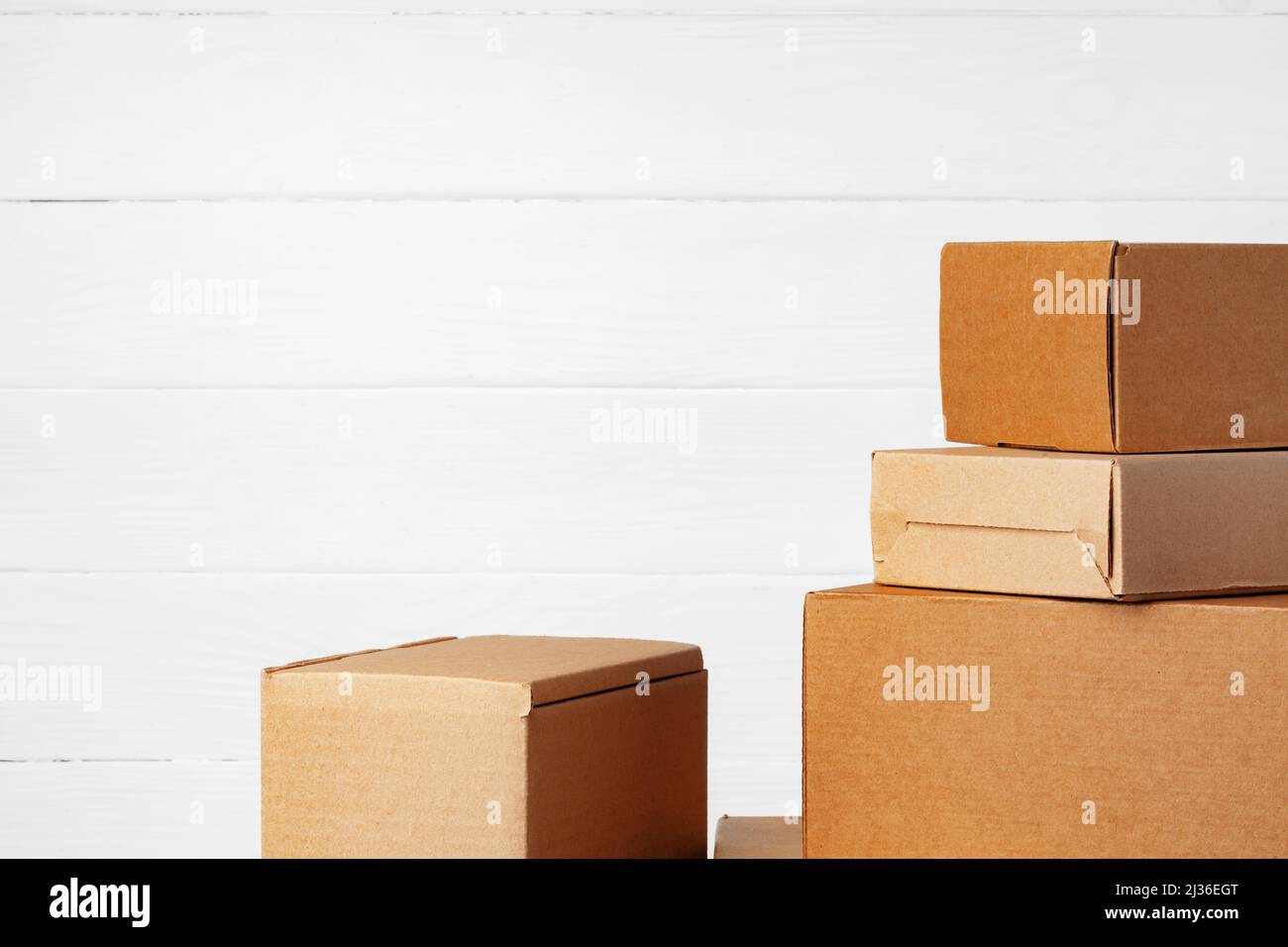 Group of cardboard boxes against white wooden wall Stock Photo - Alamy