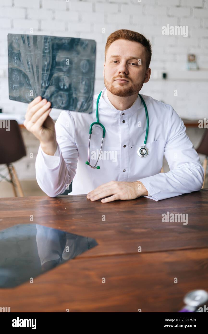 Vertical shot of serious male doctor in white uniform examining brain ...
