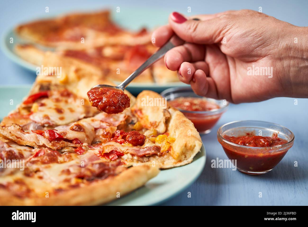 Woman's hand spreading hot sauce on a pizza slices, closeup Stock Photo ...