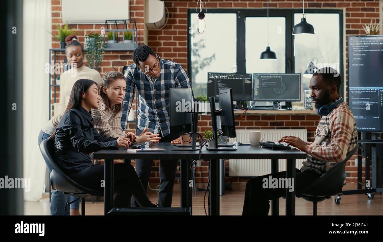 Junior developers collaborating on group project compiling algorithm asking senior programer for ...