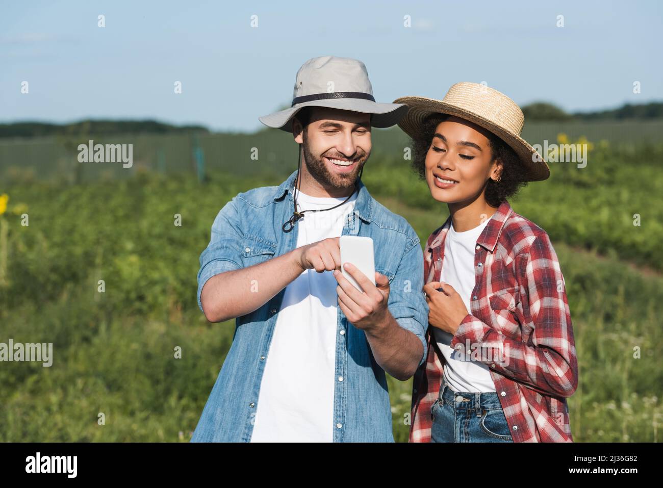 happy farmer showing mobile phone to african american woman in field ...