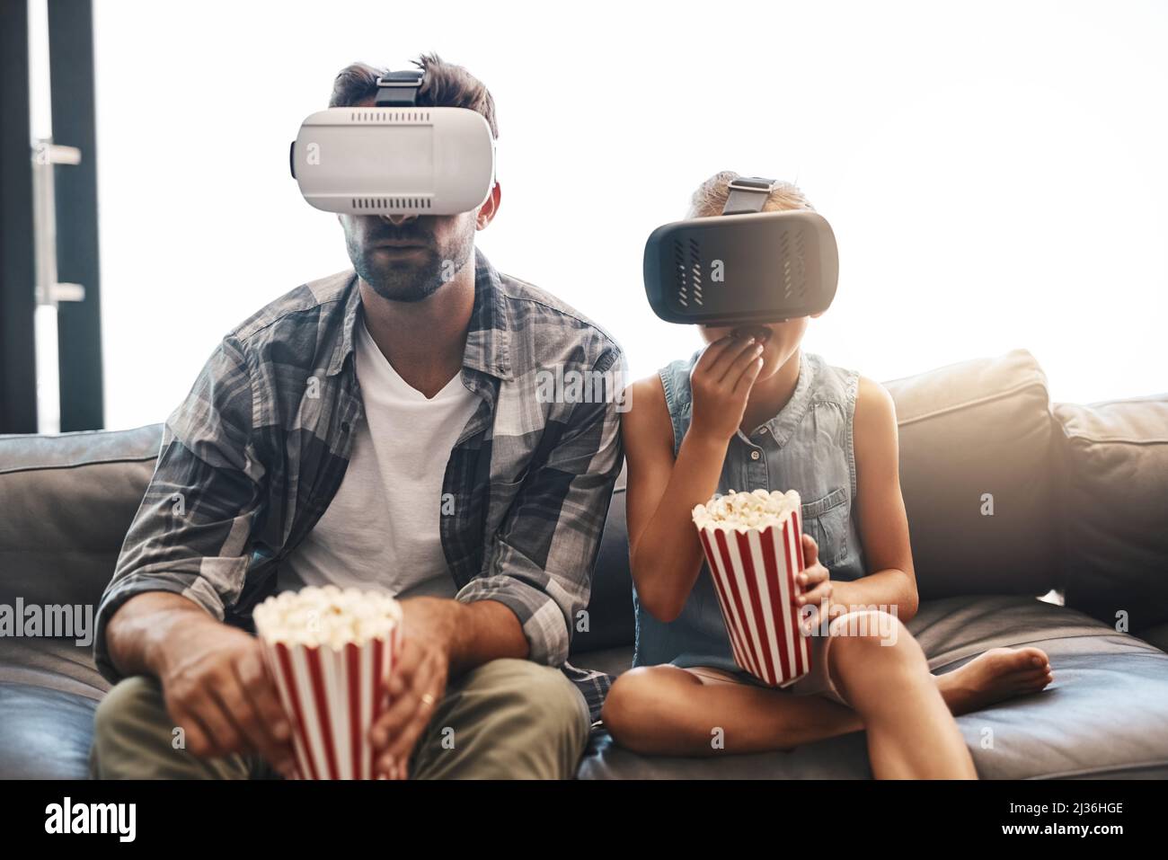 Fun for all ages. Shot of a father and daughter eating popcorn and ...