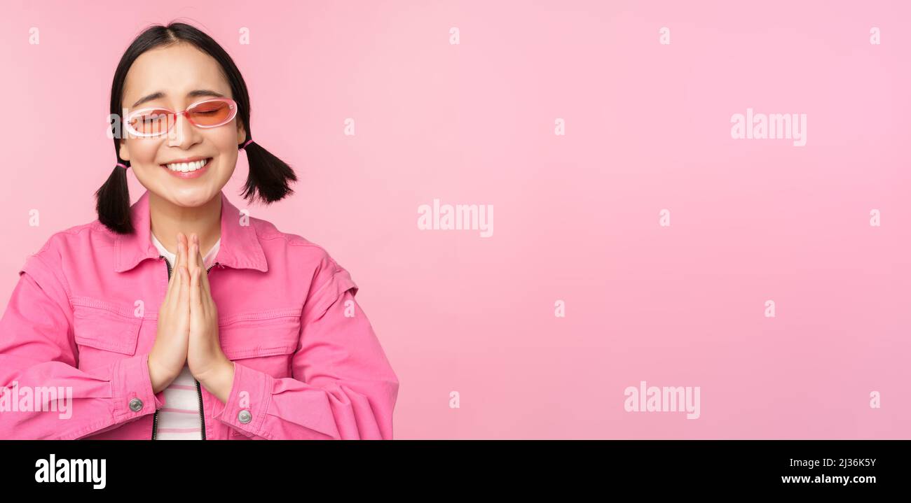 Please. Cute asian girl asking favour, begging, standing against studio ...