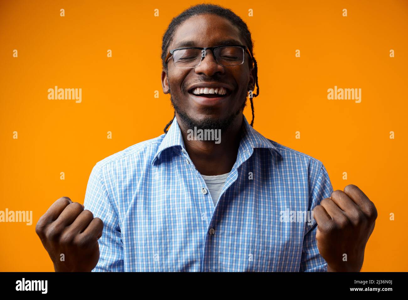 Portrait of overjoyed black man celebrating success with clenched fists ...