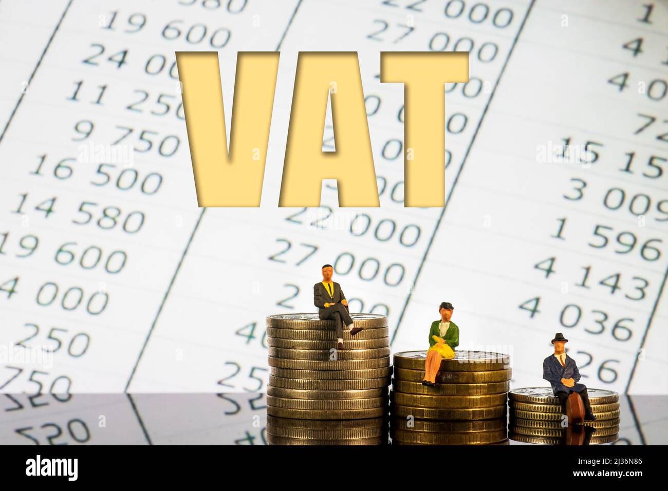Miniature people: people sitting on coins stack. VAT text accounting ...