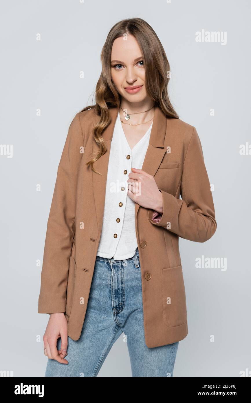 front view of smiling woman in beige blazer looking at camera isolated ...