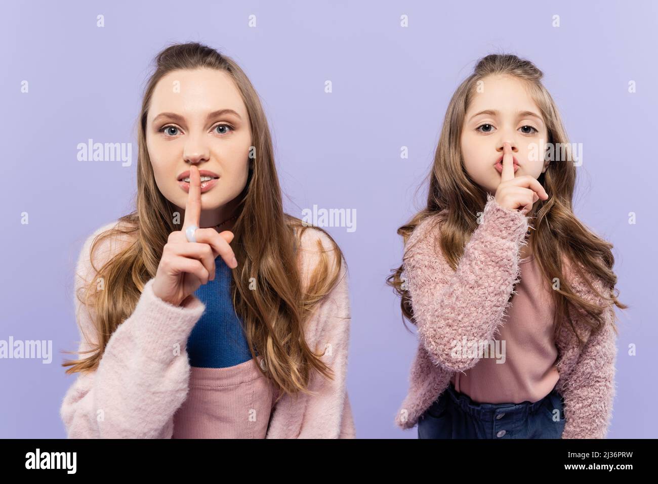 mother and daughter showing hush sign isolated on purple Stock Photo ...