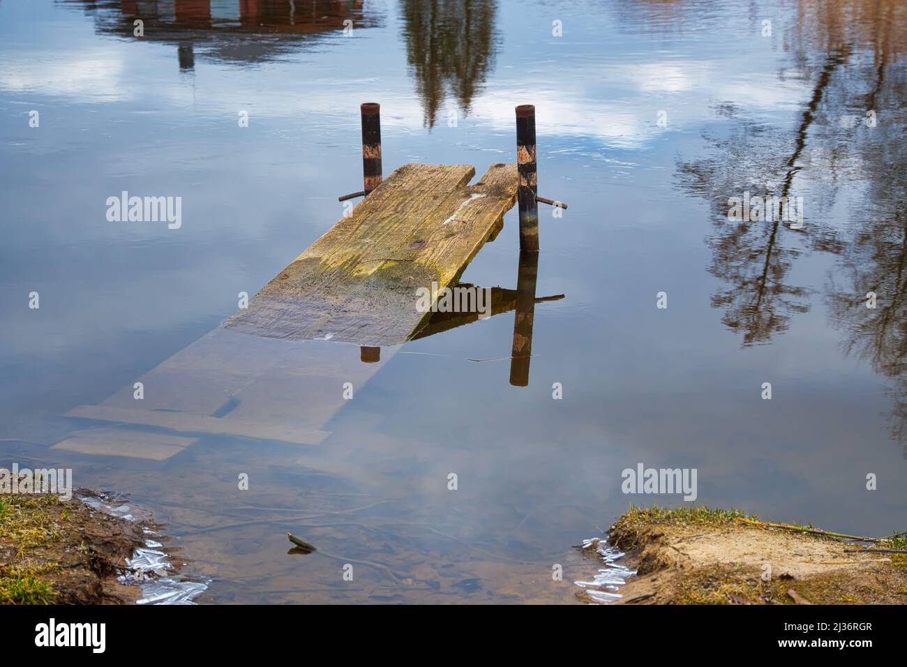 Spring flooding, old broken sunken jetty in a tranquil lake with ...