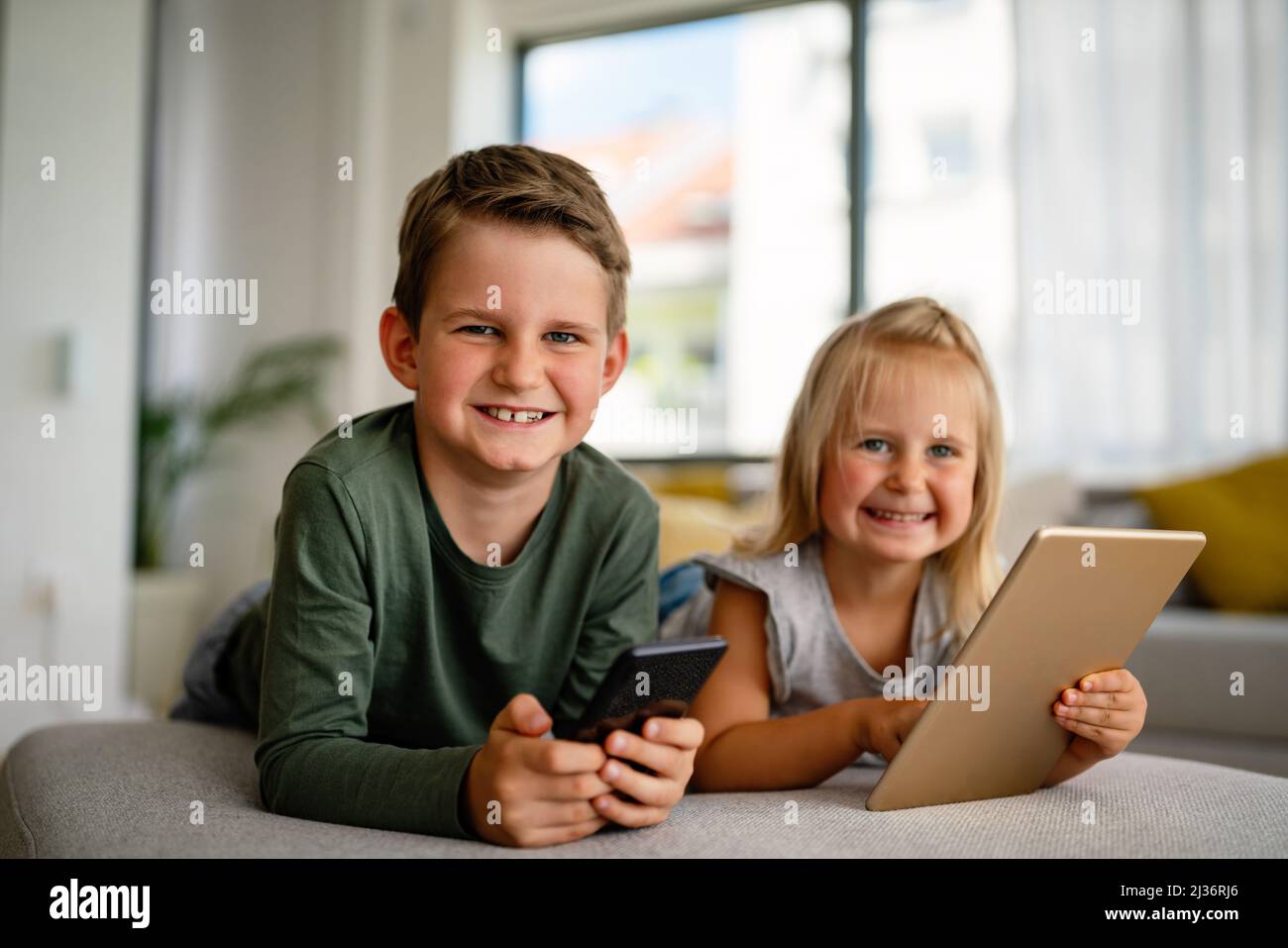 Little kids holding smartphone, tablet playing mobile game online ...