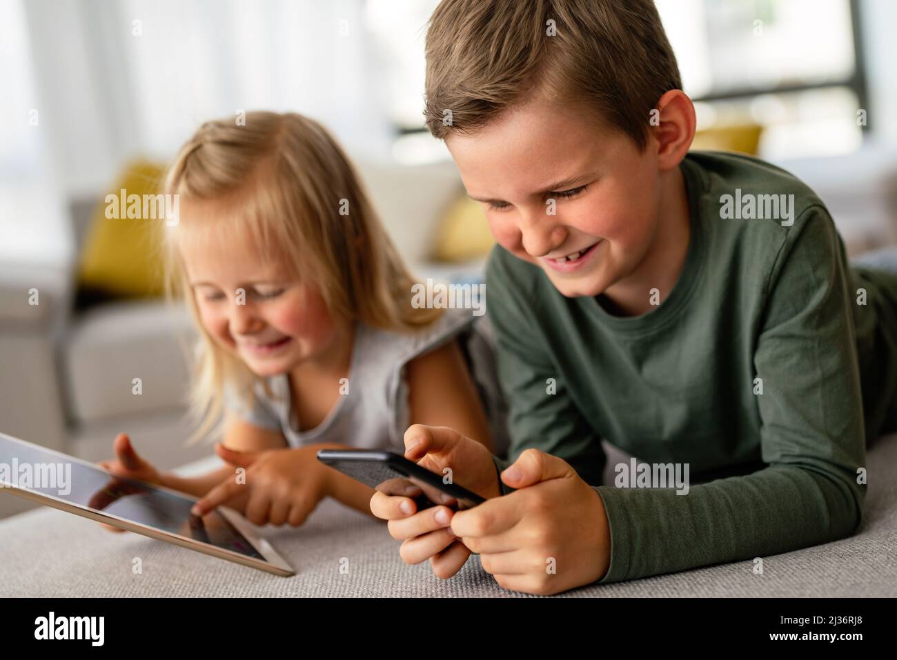 Little kids holding smartphone, tablet playing mobile game online ...