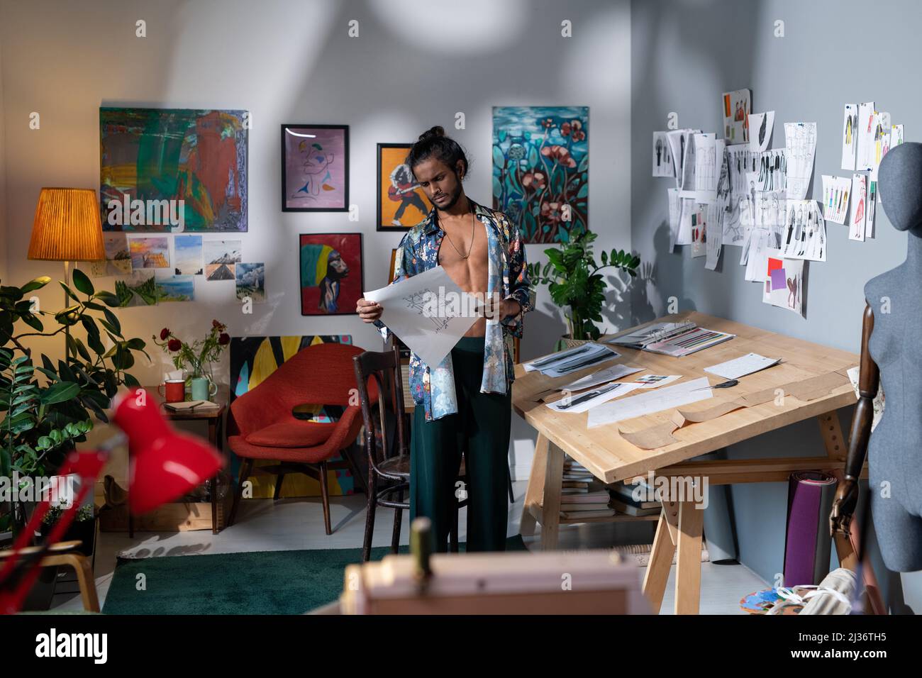 Modern young fashion designer standing in room decorated with paintings ...