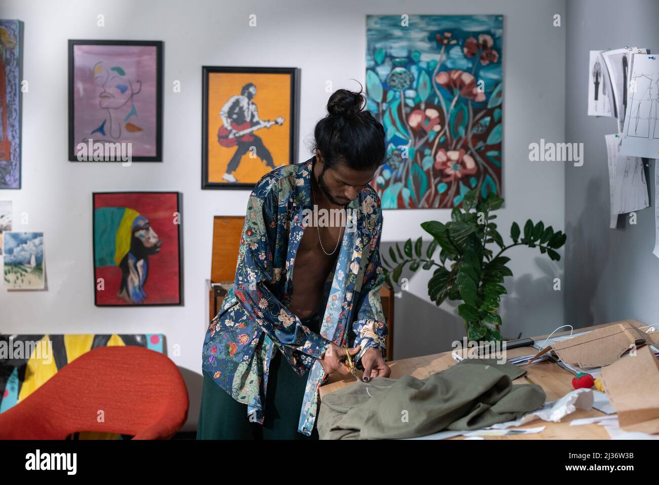 Modern fashion designer of Indian ethnicity cutting cotton fabric using ...