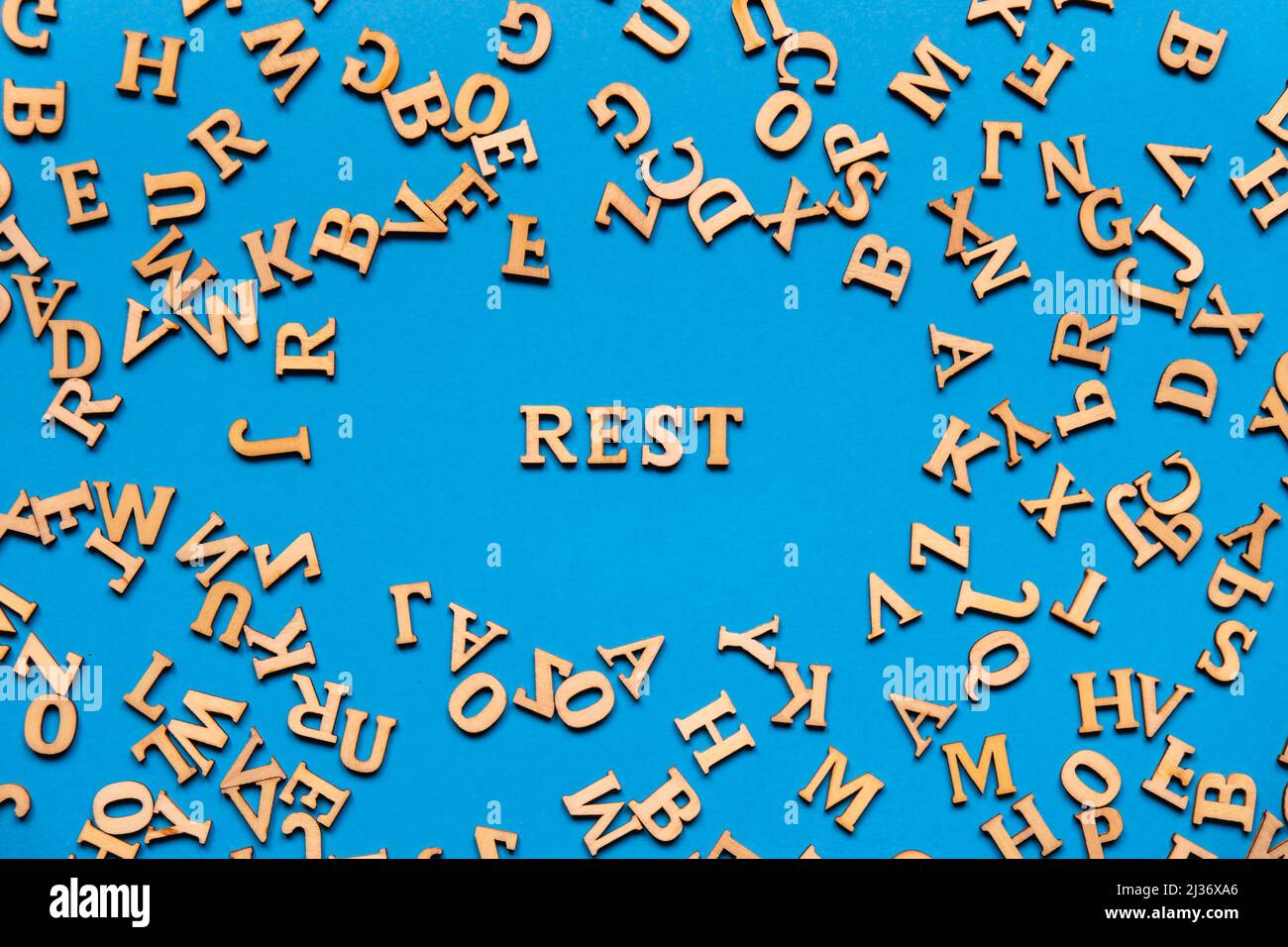 Word REST made out of wooden letters on bright blue background ...