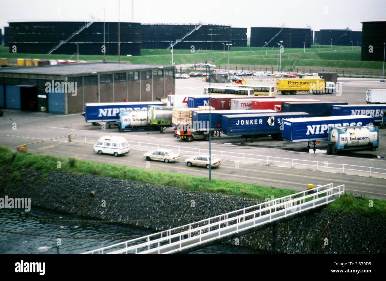 Oil storage tanks and vehicle freight containers on quayside, Port of ...