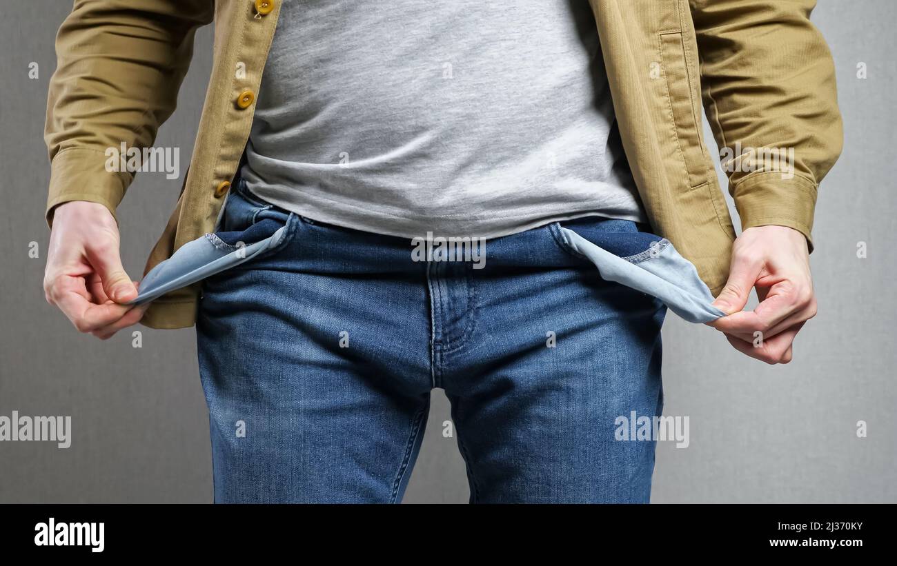 Poor man looks for money in jeans pockets on grey background Stock ...
