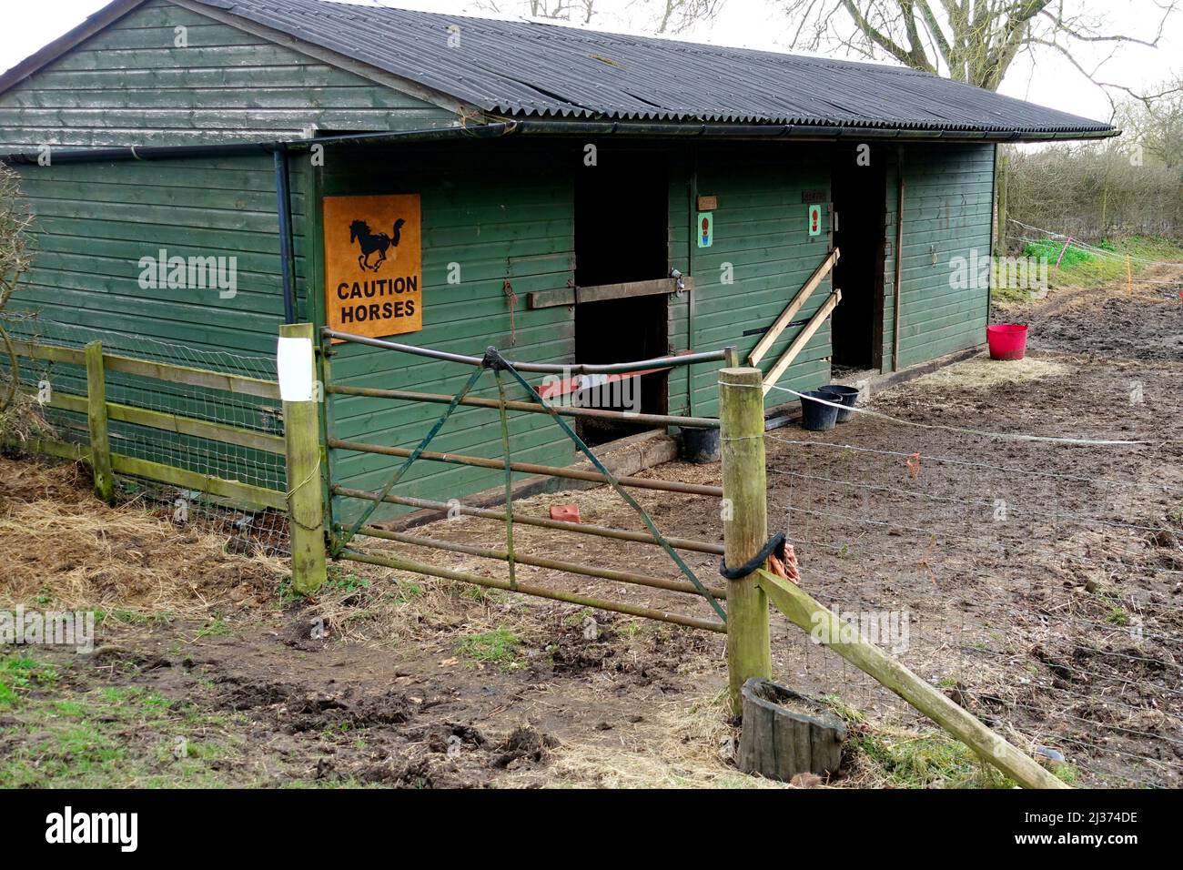 Horse stable in muddy field behind metal gate Stock Photo - Alamy