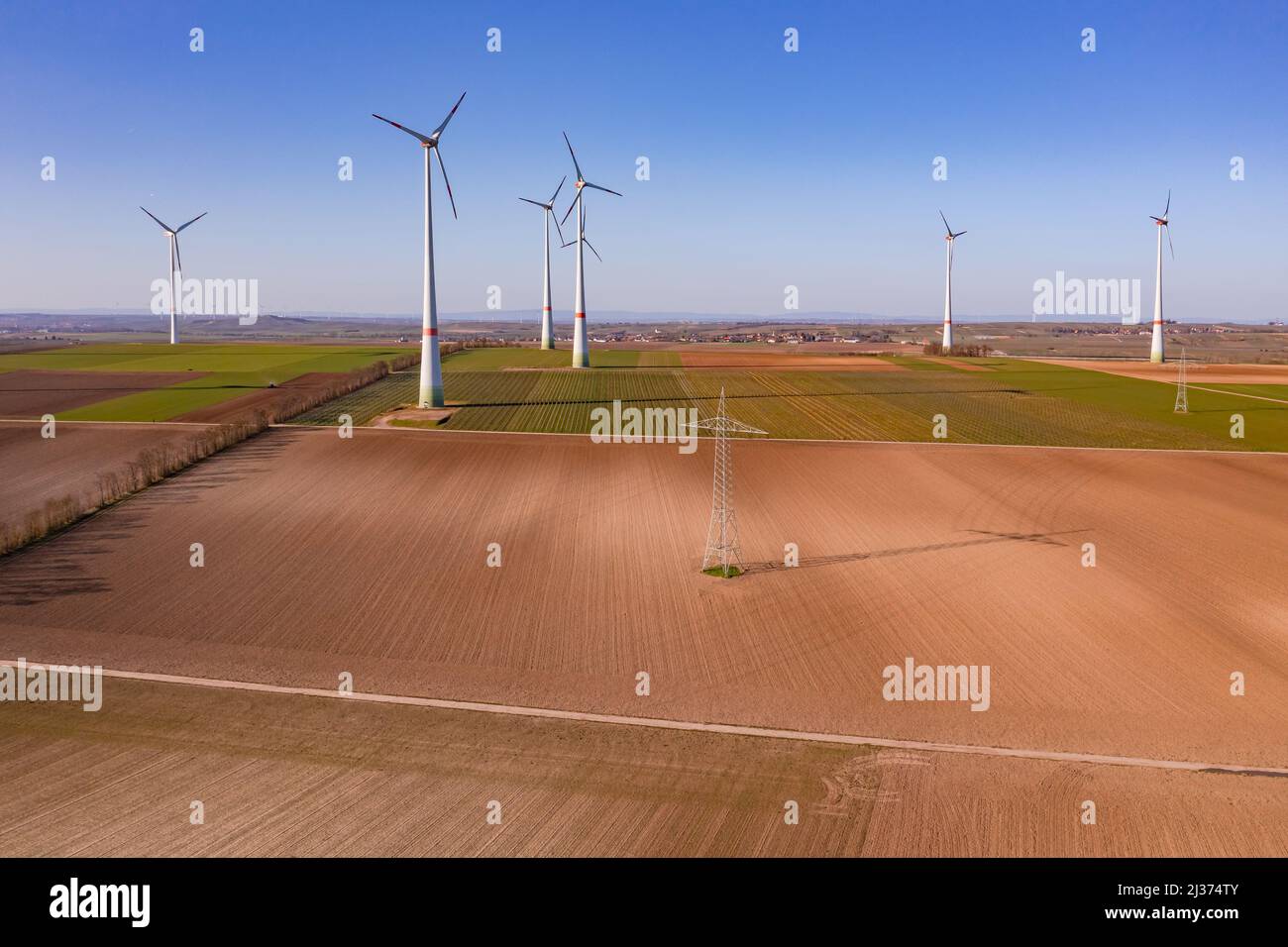 A power pole and many huge wind turbines on a field seen from above as ...