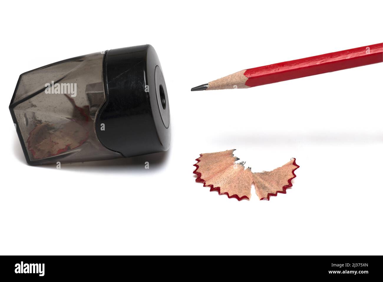 Close up of red sharpened pencil in front of sharpener lying on side ...