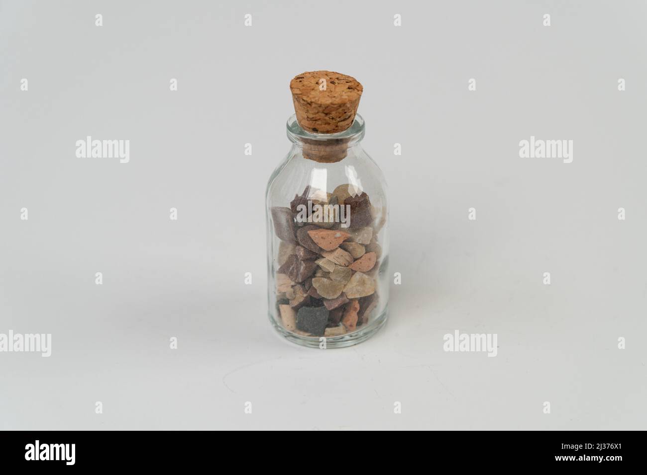 Small rocks in glass bottle with cork stopper isolated on white ...
