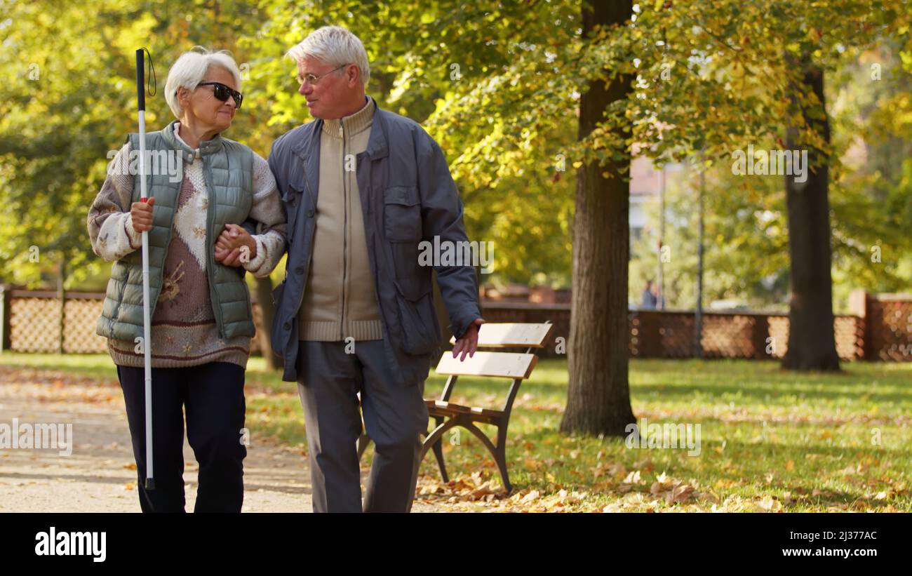 Senior Caucasian blind lady with glasses and a stick relies on her ...