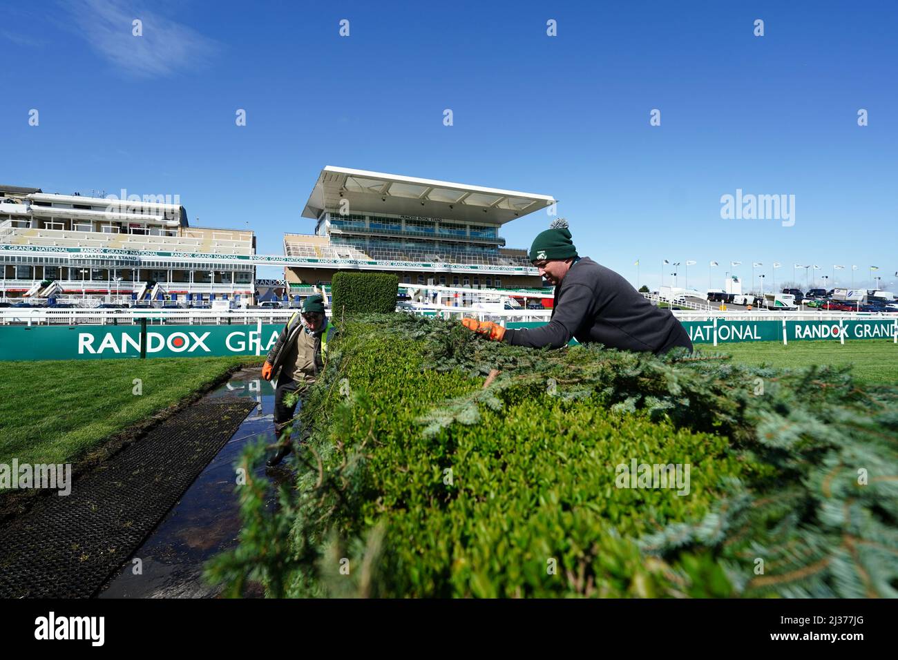 Ground staff make the final preparations to the water jump at Aintree ...