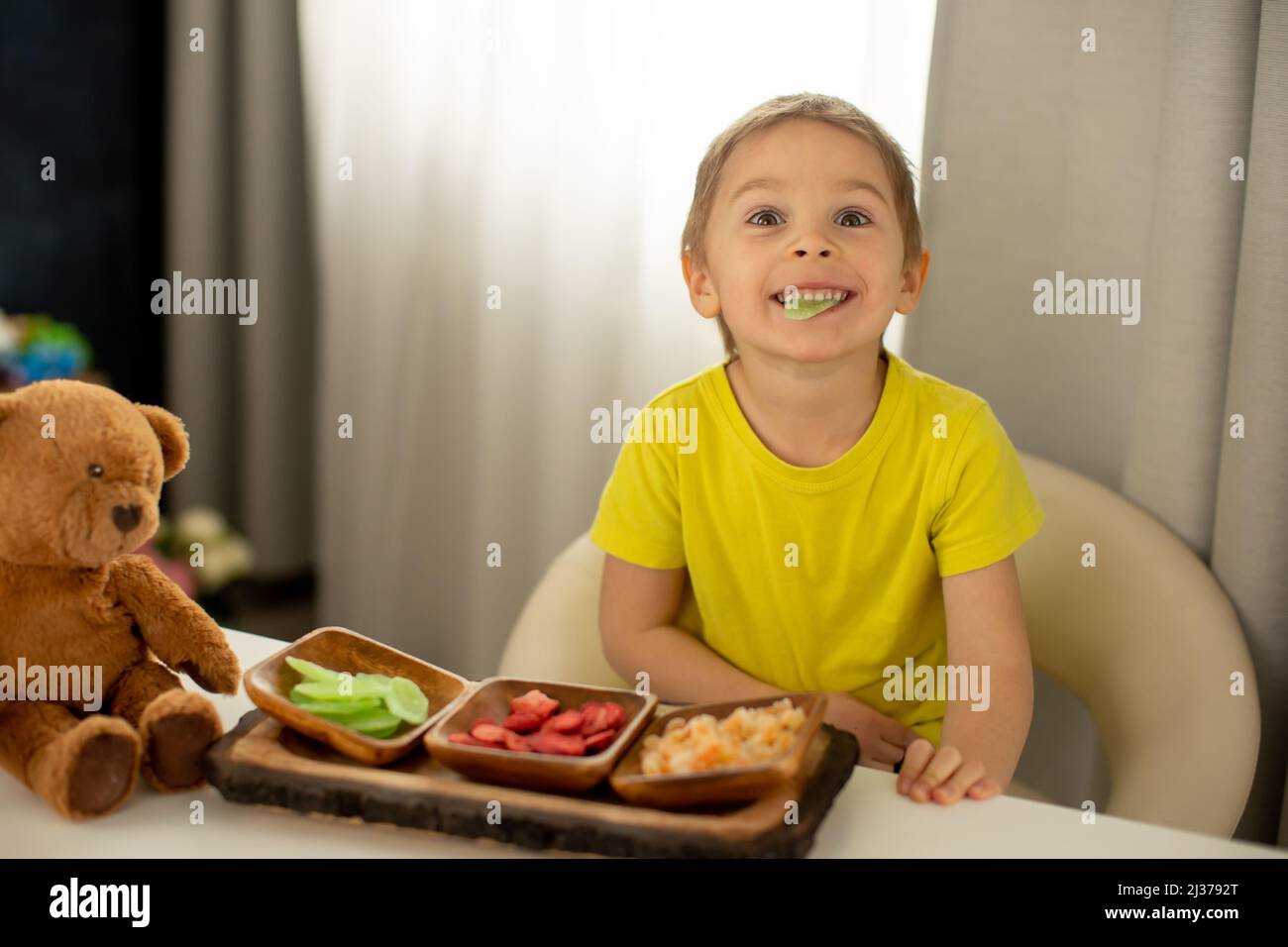 Cute little preschool child, boy, eating dried fruits at home ...