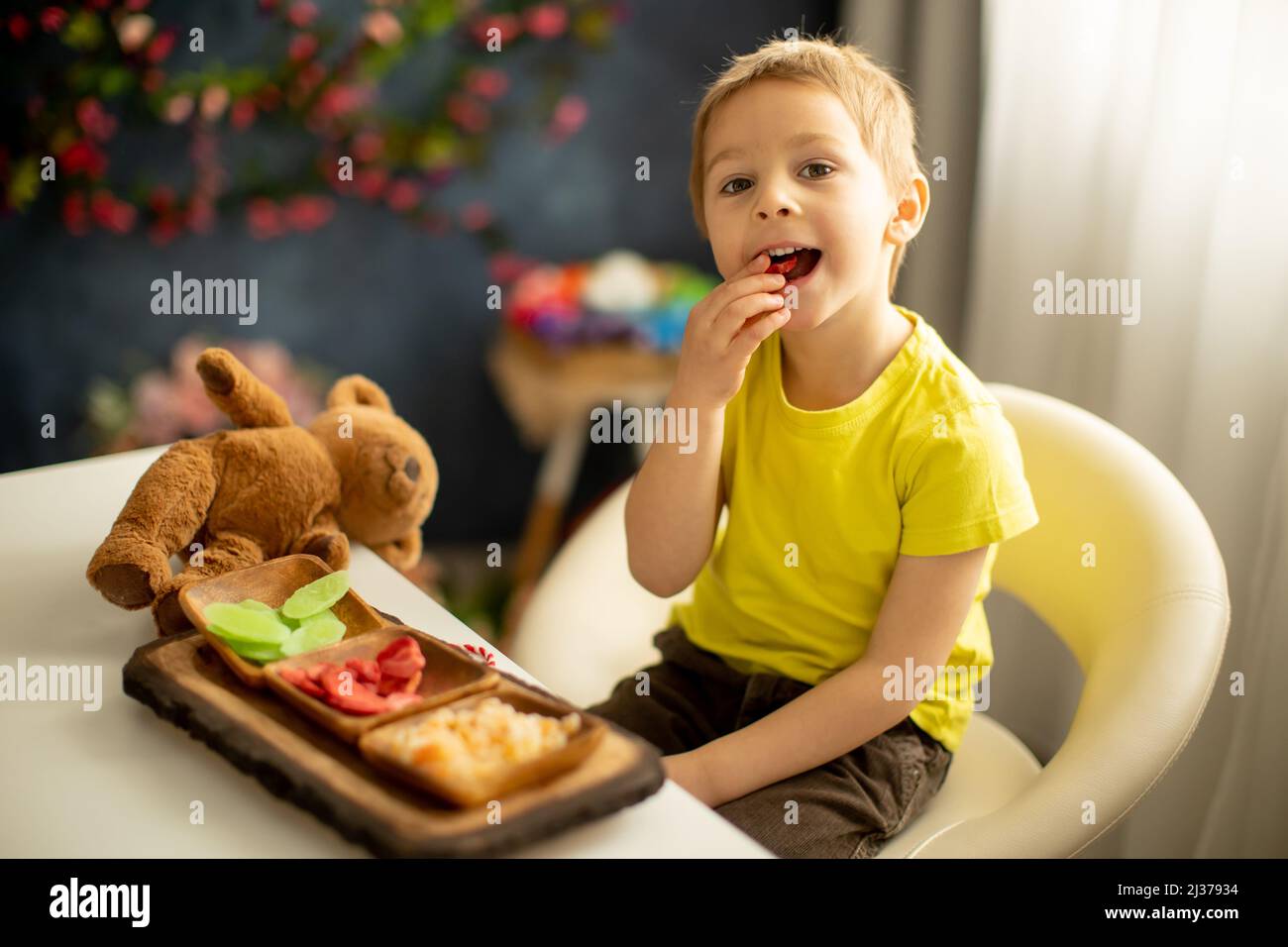 Cute little preschool child, boy, eating dried fruits at home ...