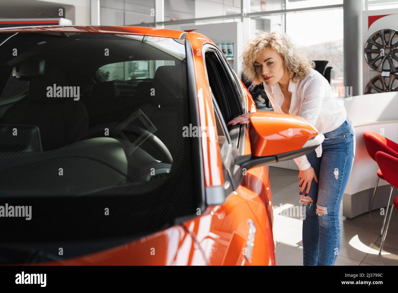Curly blonde in a car dealership. Woman chooses a new car Stock Photo ...