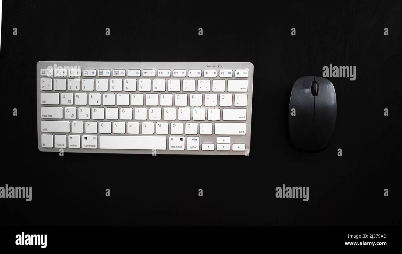 White wireless keyboard and black mouse on desk, isolated on black ...
