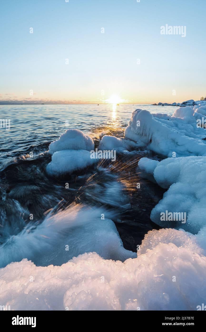 Waves splashing on the ice covered rocks in the shore of Baltic Ocean ...