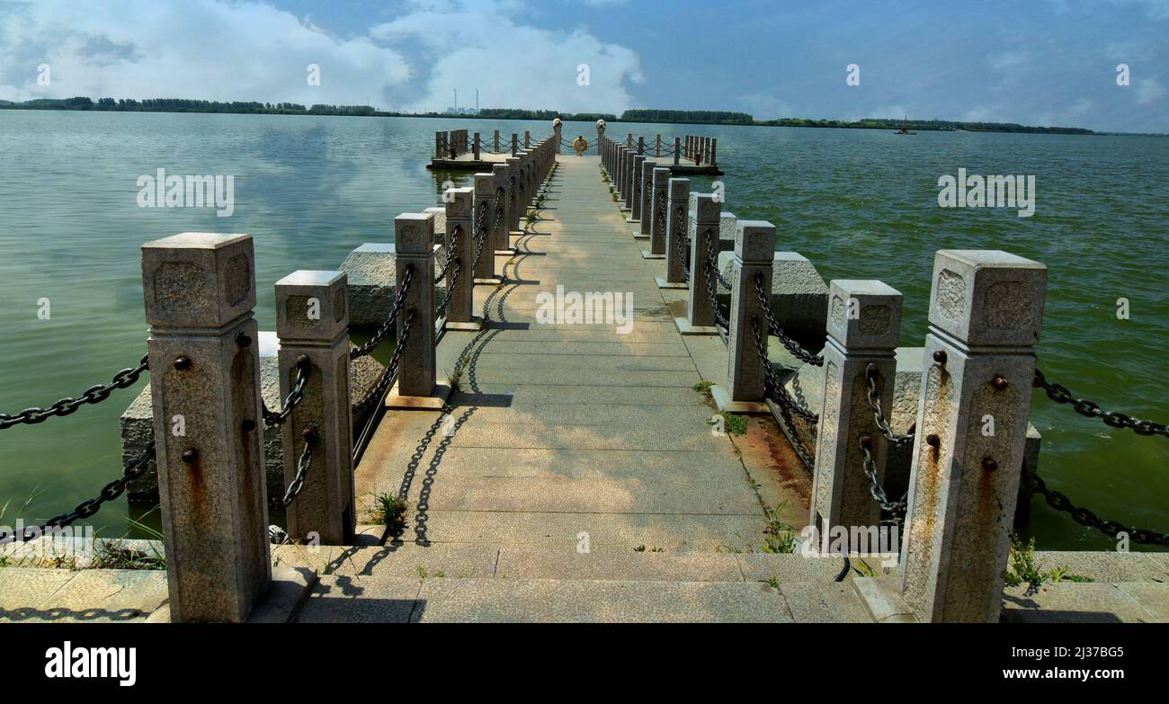 A rusty wooden dock on a green lake with clear blue sky Stock Photo - Alamy