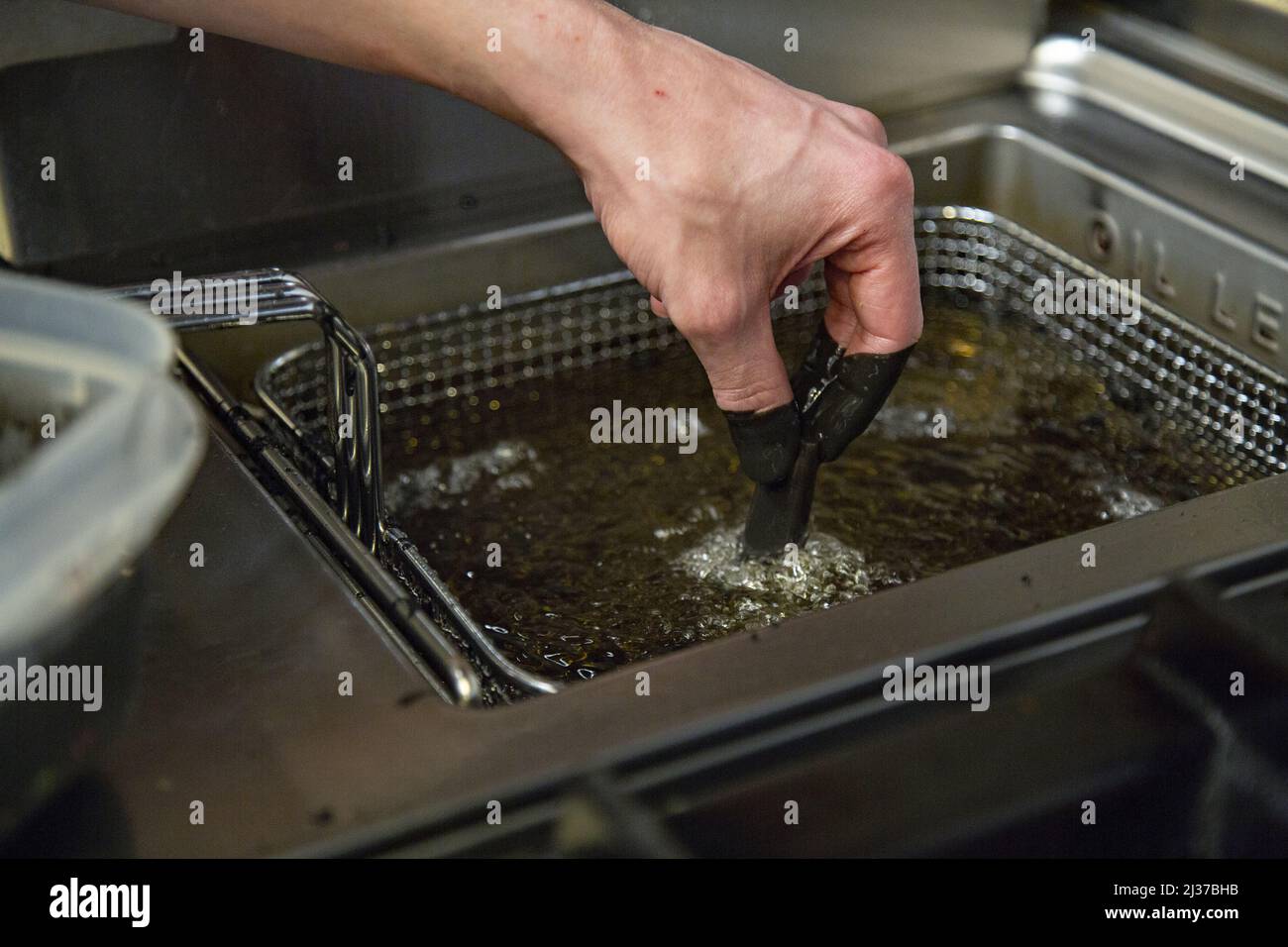 A cook holding the food in deep-fried boiling oil Stock Photo - Alamy
