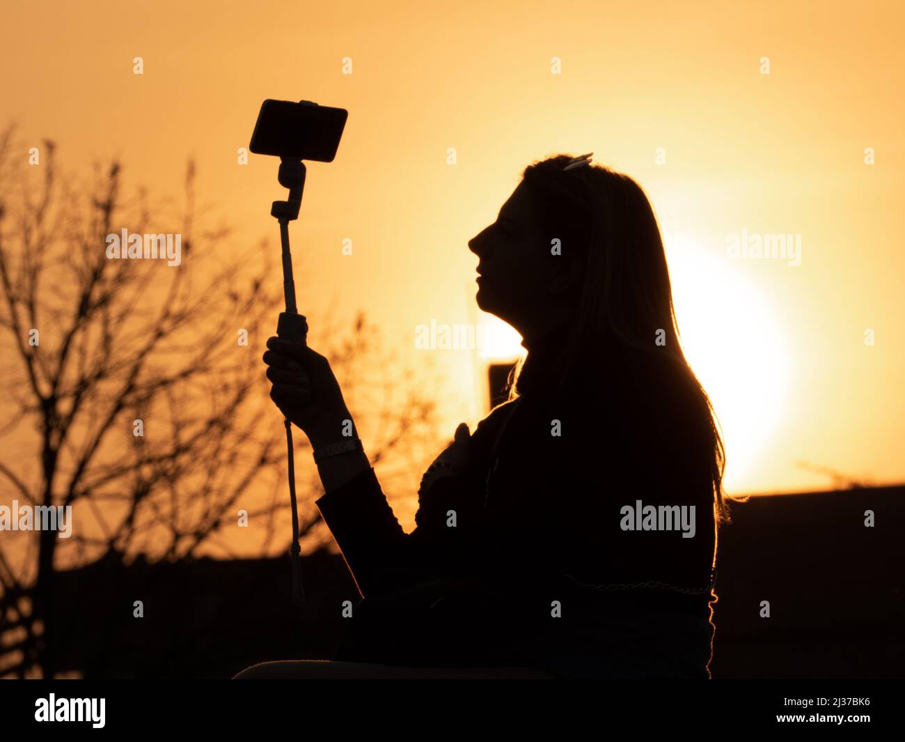 Silhouette of woman taking pictures of sunset hi-res stock photography ...