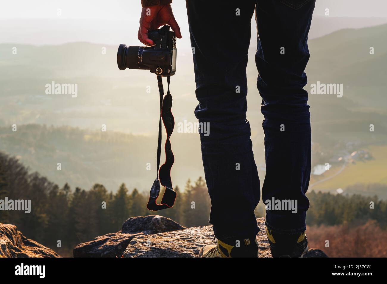 A closeup of a photographer with a camera, standing on the edge above ...