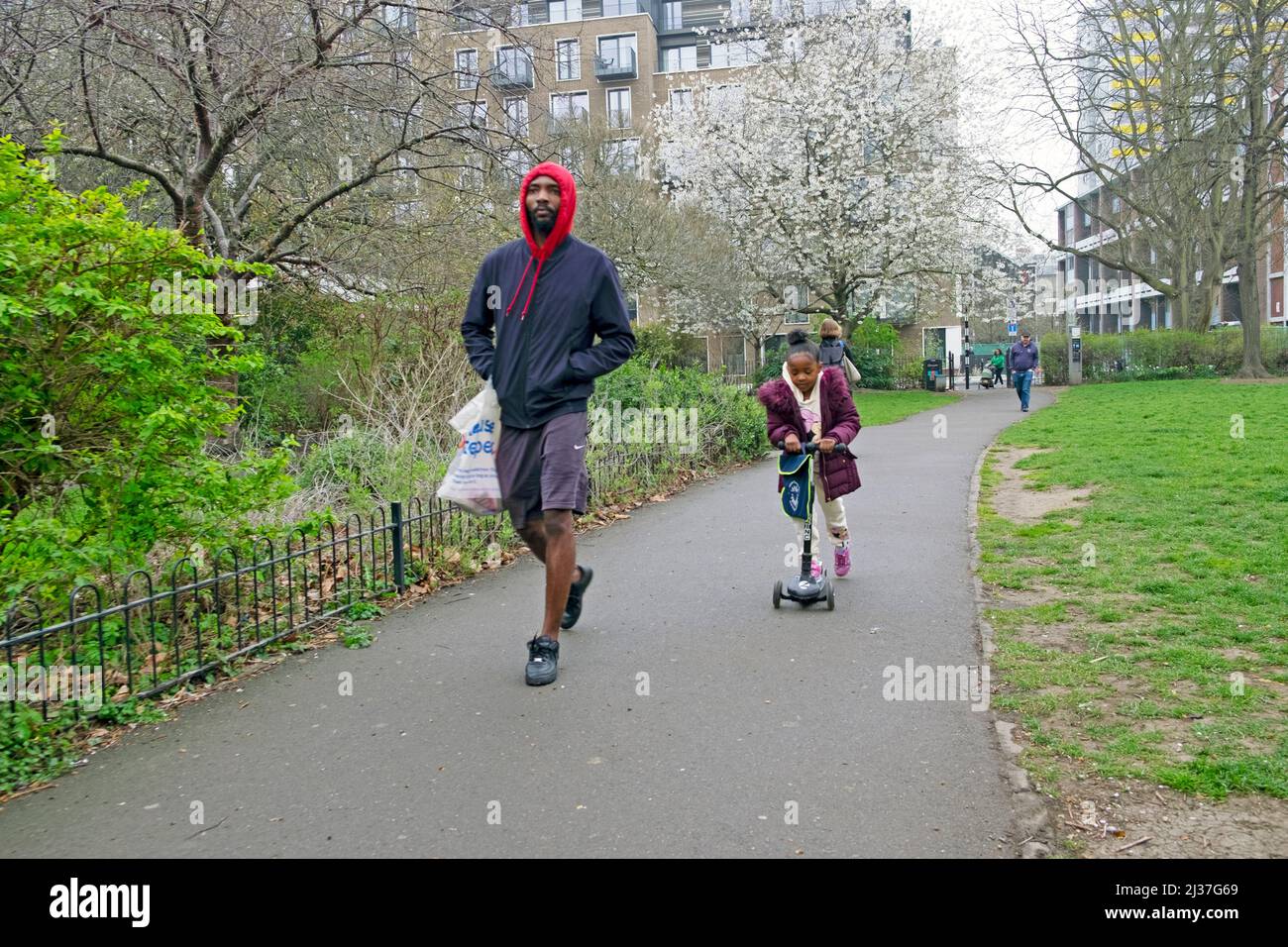 Father parent walking girl child on scooter to school through park in ...